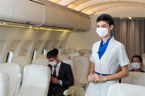 매력적인 승무원 비행기의 보호 얼굴 마스크 모자 및 드레스 정장을 입은 에어 호스티스 또는 스튜어디스의 초상화 비행기에서 보호 얼굴 마스크를 착용한 여행자 또는 승객 25