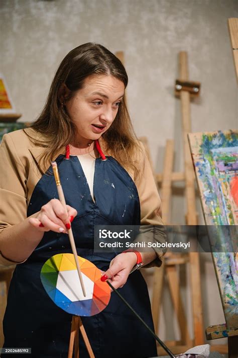 교사는 미술 수업에서 아이들에게 그림을 그리는 법을 배웁니다 작업장에서 페인팅 여자가 이젤에 붓을 그립니다 아티스트가 색상을 혼합하고 결합하는 방법을 설명합니다 교육 학습
