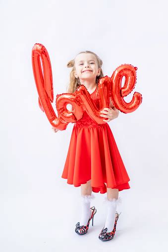 빨간 잠옷을 입은 어린 소녀 어린 소녀 빨간 하트가 있는 짙은 갈색 나무 배경에 사랑이 새겨진 큰 풍선 Farik 발렌타인 데이의 개념 4 5세에 대한 스톡 사진 및 기타