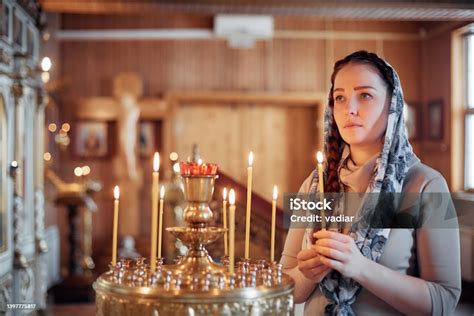 빨간 머리카락과 머리에 스카프를 씌운 러시아 정교회의 여성이 촛불을 켜고 아이콘 앞에서기도합니다 단도에 대한 스톡 사진 및 기타 이미지 Istock