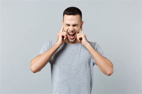 스튜디오에서 회색 배경에 고립 된 손가락으로 귀를 덮고 눈을 닫은 유지 캐주얼 옷에 젊은 남자를 좌절 비명 사람들은 진심으로 감정 라이프 스타일 개념입니다 복사 공간을 모의