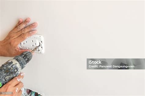 콘크리트에 소켓 플러그용 와이어 케이블을 설치하는 무선 스크루 드라이버가있는 전기 기술자의 손 주택 및 아파트 개념의 개조 수리 서비스 및 개발 나사돌리개에 대한 스톡 사진