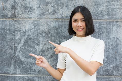 젊은 아시아 여성 포인트 시멘트 배경에서 빈 공간을 교육 개념 여자입니다 가리키기에 대한 스톡 사진 및 기타 이미지 가리키기 개성 개념 교육 Istock