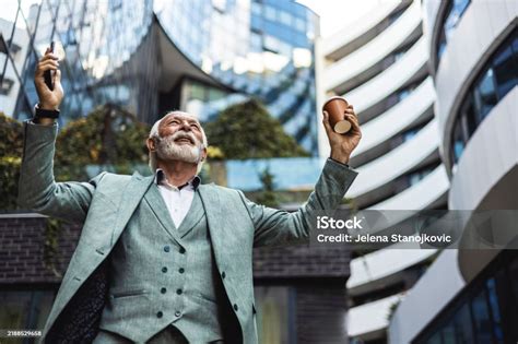 사무실 건물 밖에서 성공하고 행복한 백발의 상사는 성공과 승리를 기뻐하고 손을 들고 승리하고 사업가 비즈니스 정장을 입은 사업주 성숙한 투자자 은행가입니다 65 69세에