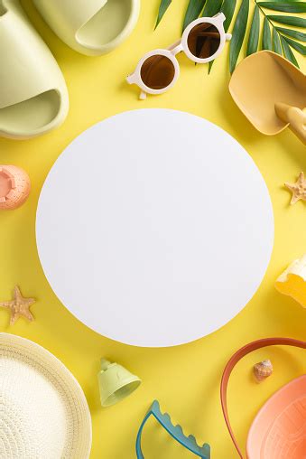 휴가 개념에 아이를 위한 재미있는 활동 슬리퍼 파나마 선글라스 해변 어린이 장난감 야자수 잎 조개껍데기가 있는 빈 원의 상단 수직 보기 사진 복사 공간이 있는 노란색 격리된