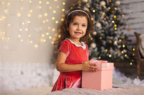 可爱的小女孩微笑着，拿着粉红色的礼物盒