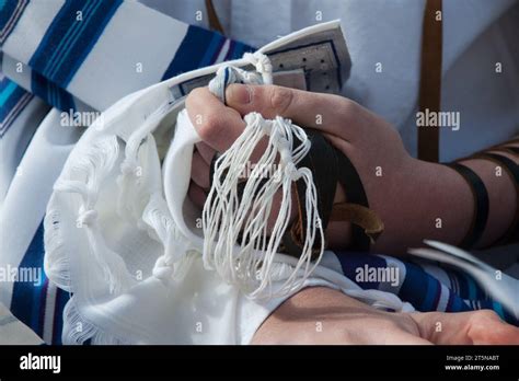 A Jewish Man Grasps The Strings Of His Tallit Or Tzitzit While Reciting