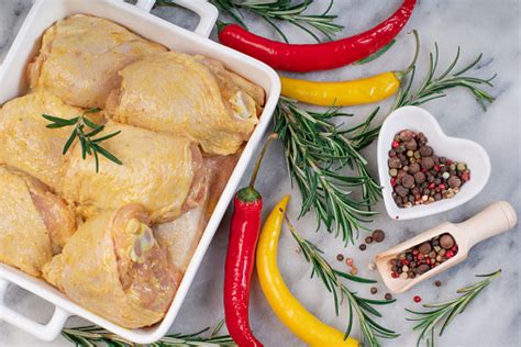 상단 보기 클로즈업 신선한 로즈마리 잔가지와 대리석 주방 보드에 다양한 향신료와 흰색 오븐 베이킹 접시에 노란색 양념 에 원시 양념 치킨 허벅지 가금류에 대한 스톡 사진 및