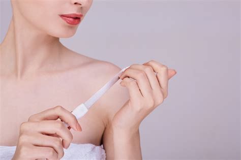 반쯤 벗은 여자는 밝은 배경에 손톱을 정리합니다 프리미엄 사진