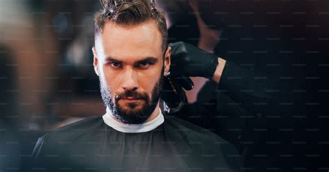 검은 보호 마스크를 쓴 남자가 이발소에 앉아 이발을 하는 젊은 수염 난 남자의 전면 모습 사진 Unsplash의 우크라이나 이미지