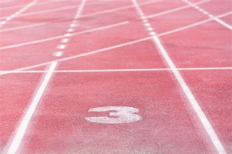 운동하는 스포츠맨을 위한 빨간색 고무 육상 트랙에서 숫자 3과 흰색 선 교차 프리미엄 사진