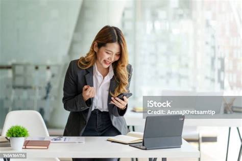 목표를 달성하는 성공적인 젊은 아시아 비즈니스 여성은 사무실에서 노트북을 들고 기뻐하며 손을 들었습니다 새로운 시작 프로젝트 개념입니다 20 24세에 대한 스톡 사진 및