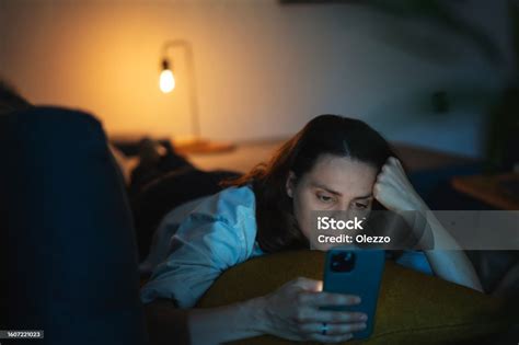 소파에 누워 집에서 밤에 스마트폰 화면을 보고 있는 젊은 진지한 슬픈 여자 전화에 대한 스톡 사진 및 기타 이미지 전화 밤 하루 시간대 사람들 Istock