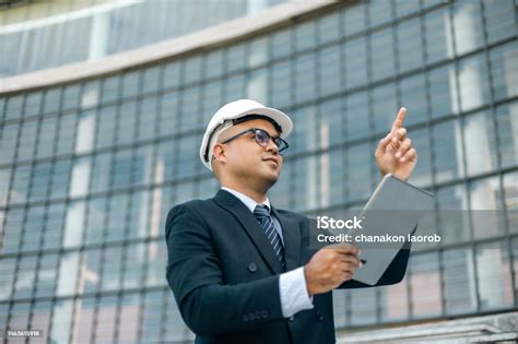 현대 사무실 건물에서 디지털 태블릿으로 일하는 사업가 관리자 소유자 건축가 디자이너의 협력 작업 현장에서 안전 헬멧을 착용한