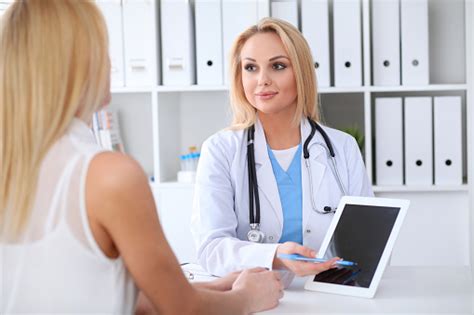 의사 그리고 환자 병원에서 테이블에 앉아있는 동안 뭔가 논의 의사 정보 데모에 대 한 태블릿 Pc를 사용 하 여입니다 의학 및 건강 관리 개념입니다 가리키기에 대한 스톡