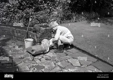 1970s Historical Outside On A Crazy Paved Patio An Elderly Lady