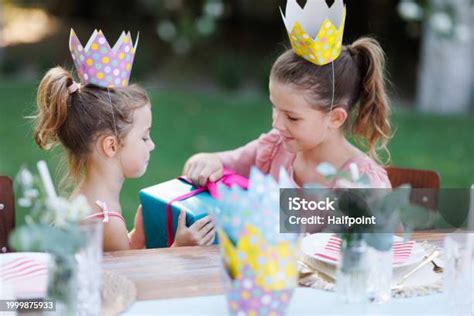 정원에서 야외에서 생일 파티를 하는 작은 친구들 생일 선물을 여는 종이 왕관을 가진 귀여운 소녀들 어린이를 위한 생일 가든 파티 아이에 대한 스톡 사진 및 기타 이미지