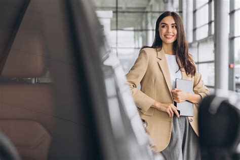 미소 짓는 자동차 판매자 베이지 색 양복을 입은 사업가가 자동차 살롱에 서서 올바른 자동차를 선택하기 위해 태블릿을 사용합니다 25 29세에 대한 스톡 사진 및 기타 이미지