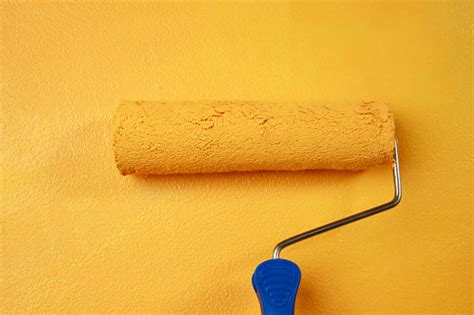 롤러 브러쉬 페인팅 노란색 페인트로 개조 표면 벽 페인팅 아파트에 노동자 그림 빈 복사 공간을 흰색으로 남겨 옆에 설명 텍스트를 작성합니다 벽에 대한 스톡 사진 및 기타