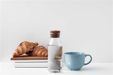 코르크 스토퍼가 있는 투명한 병 흰색 배경에 신선한 크루아상이 있는 머그컵과 책 실내 장식소재의 천연 및 친환경 소재 공간을 복사하고 모의합니다 0명에 대한 스톡 사진 및