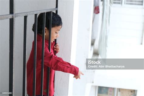 흰색 도시 배경의 발코니에 서있는 동안 활기찬 빨간 셔츠를 입고 인도 귀여운 작은 쾌활한 갈색 머리 타밀 아기 소년의 초상화 2