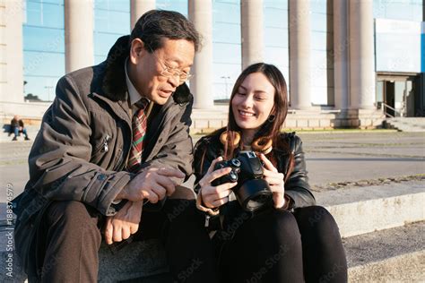 Japanese Grandfather And Granddaughter Looking The Pictures They Took