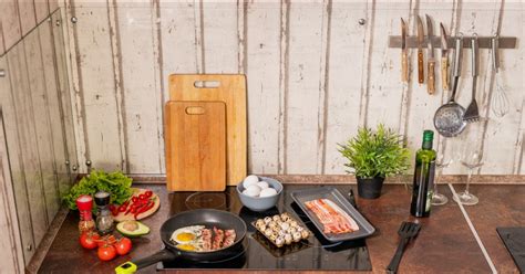 신선한 과일과 채소 향신료 나무 판 올리브 오일 한 병으로 둘러싸인 베이컨으로 계란을 요리하는 동안 프라이팬이 있는 전기 스토브 사진 Unsplash의 성분 이미지