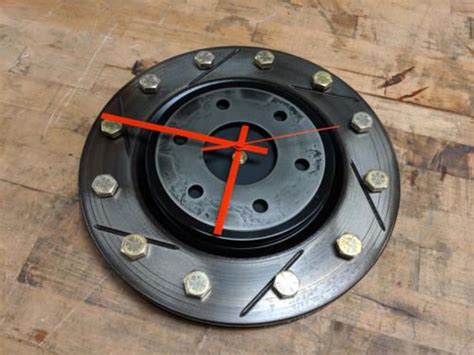 A Close Up Of A Clock On A Wooden Floor With An Orange Arrow Pointing To It