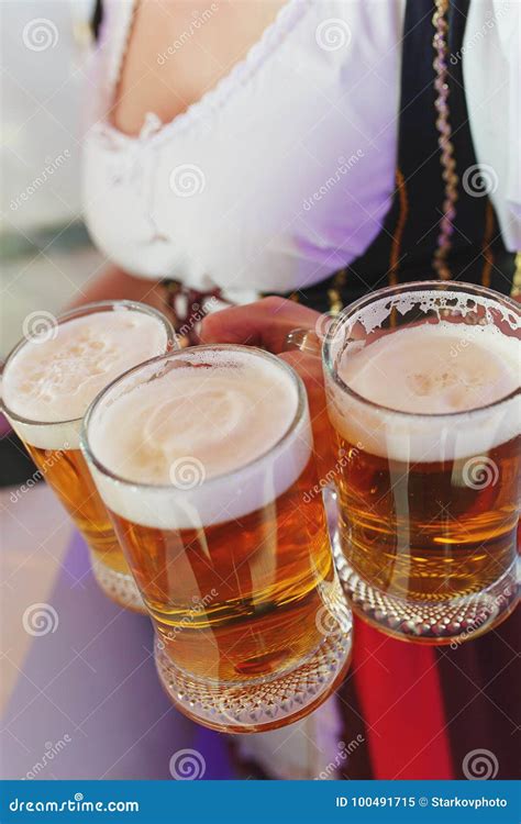 Girl In A Traditional Dress With A Big Breasts And Deep Neckline Holds Full Mugs Of Beer Stock
