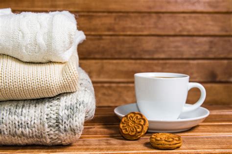 아늑한 니트 따뜻한 스웨터 나무 배경의 스택 레트로 스타일과 뜨거운 음료 컵에 스웨터 온 정 및 안락의 개념입니다 가을에 대한