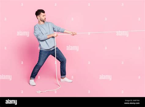 Profile Side Full Body Photo Of Guy Pulling String Have Victory Motivation Isolated On Pastel