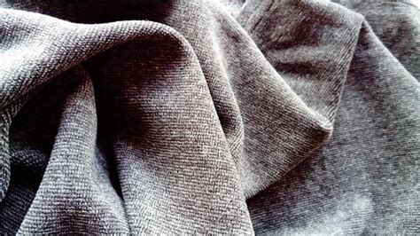 약간 파도에 접히거나 주름이 있는 회색 벨벳 원단의 클로즈업과 질감 자연 일광에 커튼에 빛과 그림자의 놀이 부드럽고 두껍고 따뜻한 합성 폴리 에스테르 소재 명암 대조에 대한