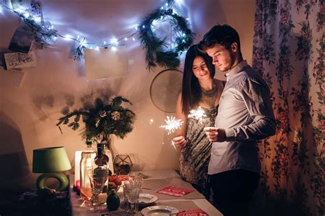 집에서 새해 전야를 축하하는 불타는 스파클러 벵골 빛을 들고 세련된 커플 메리 크리스마스 개념 함께 겨울 휴가를 축하 불꽃