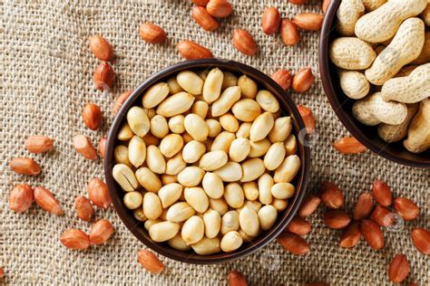 Арахис в скорлупе и очищенный от кожуры крупным планом в чашке Ozero российский фотосток