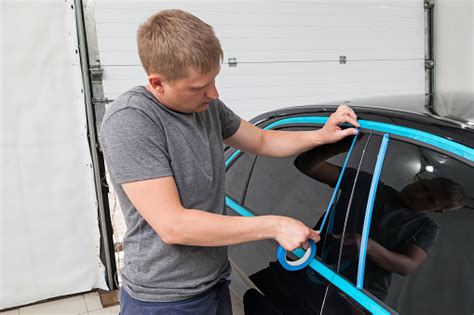 파란색 종이 테이프와 백인 외관의 남자는 페인트와 니스를 연마하고 차량 세척 및 세부 작업장에서 스크래치를 제거하기 위해 검은 색 자동차와 몸 요소 문 창을 석고 걸레에