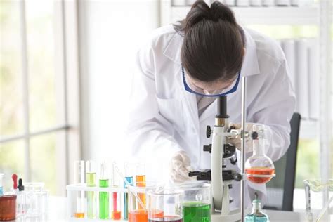 Premium Photo Woman Using Microscope By Test Tubes And Beaker With Liquids On Table