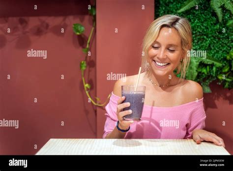 Cheerful Woman Smiling While Enjoying Drinking A Delicious Smoothie In
