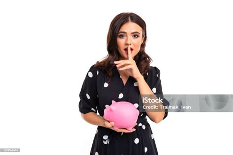 유쾌한 미소 평평한 이빨 빨간 립스틱 긴 물결 모양의 밤 머리 아름다운 메이크업 완두콩의 검은 색과 흰색 드레스가 돼지 머니 박스를 들고있는 어린 소녀 경제에 대한 스톡