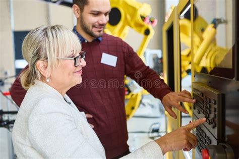 Engineers Programming Robotic Arm For Industrial Automation In Factory