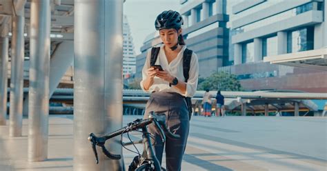 배낭을 멘 아시아 사업가는 자전거를 타고 거리에 서서 도시에서 카메라를 사용하여 사무실에서 일하러 간다 스포츠 소녀는 일을 위해 전화를 사용합니다 출퇴근 시내 비즈니스