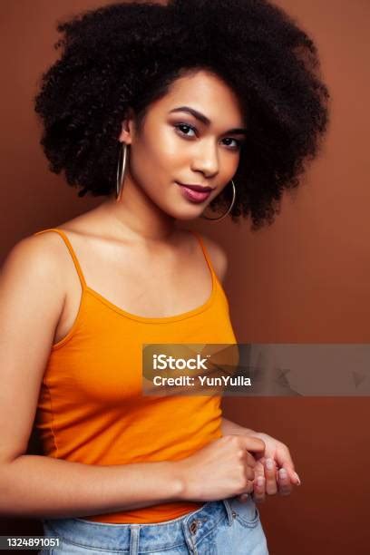 갈색 배경 라이프 스타일 사람들 개념에 쾌활한 몸짓을 포즈 곱슬 머리를 가진 예쁜 젊은 아프리카 계 미국인 여성 갈색에 대한 스톡 사진 및 기타 이미지 Istock