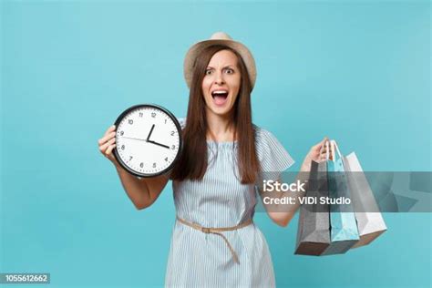 초상화 아름 다운 여름 드레스 밀 짚 모자 지주에 젊은 백인 여자 쇼핑 블루 파스텔 배경에 고립 시계 라운드 후 구매 가방 패키지 광고에 대 한 공간을 복사 합니다 가방에