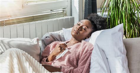 질병 계절성 바이러스 문제 개념 독감에 걸린 여자가 소파에 누워 온도계의 온도를 보고 있다 고열로 침대에 누워있는 아픈 여자 감기 독감과 편두통 사진