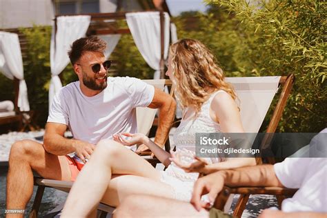 여름 방학 동안 리조트의 수영장 옆 데크 의자에 앉아 대화와 여가 시간을 즐기는 젊은이들 1개월에 대한 스톡 사진 및 기타 이미지 1개월 20 24세 30 34세