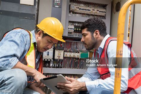 디지털 태블릿 점검 수리 유지 보수 작업 전기 시스템을 갖춘 전문 남성 전기 기술자 건설 현장에서 태블릿을 사용하는 전기 시스템을 사용하는 두 명의 남성 전기 기사 2명에