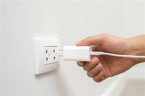 Premium Photo Close Up Hand Plugging Adapter Charge The Battery With Outlet Socket Plug And