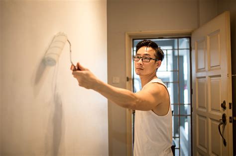 그의 새 집에서 페인트 롤러를 사용하여 벽을 그리는 아시아 중국 성숙한 남자 홈 화장 및 리노베이션 개념 Diy에 대한 스톡 사진 및 기타 이미지 Istock