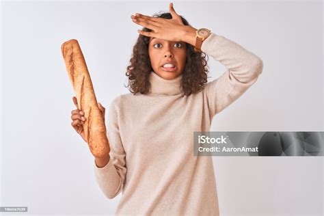 고립된 흰색 배경 위에 빵을 들고 있는 젊은 브라질 제빵사 여성은 부끄러움과 깜짝 놀란 얼굴 분노와 좌절로 충격을 받았다 실수에 대한 두려움과 화가 감정에 대한 스톡 사진