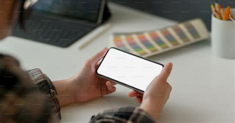 흰색 테이블에서 태블릿과 디자이너 용품으로 작업하는 동안 수평 모형 스마트폰을 들고 있는 여성 디자이너의 자른 샷 사진 Unsplash의 태국 이미지