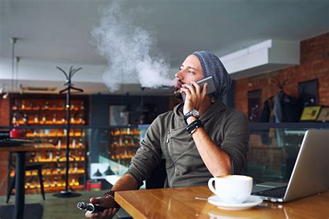 커피 Vaping 자료의 컵으로 카페에 앉아 수염과 젊은 잘생긴 Hipster 남자 증기의 구름 휴대 전화를 얘기 하 고 작은 휴식 20 29세에 대한 스톡 사진 및 기타